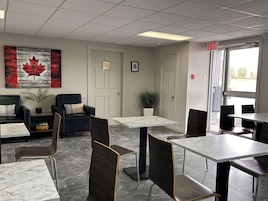 Uma sala de jantar moderna com mesas e cadeiras de mármore, uma obra de arte com a bandeira do Canadá e o sinal de um banheiro.