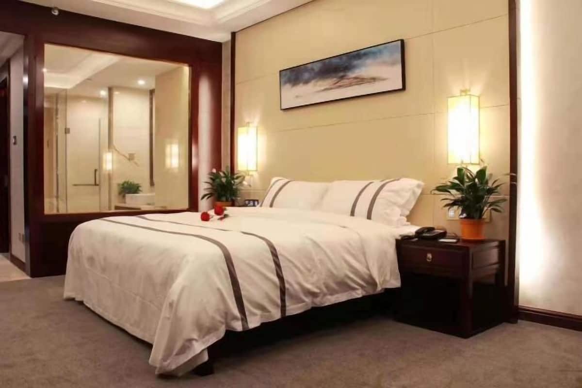 Quarto de hotel com cama, mesas de cabeceira, espelho e um quadro na parede.