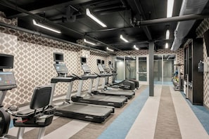 Uma academia com esteiras, bicicletas ergométricas e aparelhos de musculação.