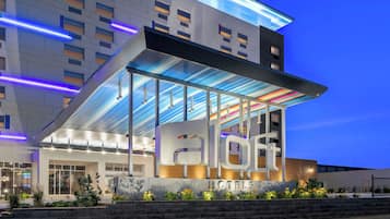 Hotel com design moderno, destacando uma fachada de vidro e um terraço no último andar.
