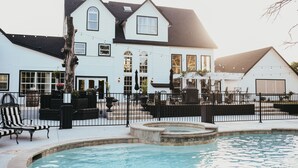 Uma casa grande e branca com piscina, área de estar externa e luzes de fada.
