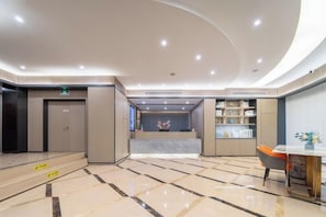 Um hall de hotel moderno com balcão de recepção, elevadores e área de estar.
