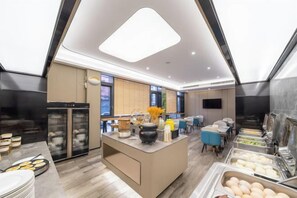 Cozinha moderna com ilha central, eletrodomésticos embutidos e área de jantar com cadeiras azuis.