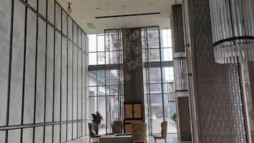 Um hall espaçoso com teto alto, amplas janelas e área de estar com cadeiras e um sofá.