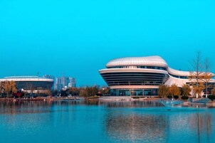 Um edifício moderno com arquitetura curva e singular à beira da água.