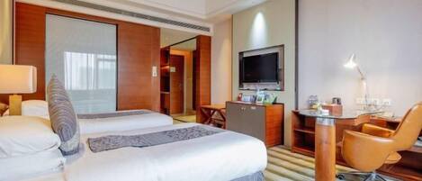 Quarto de hotel com uma cama grande, uma mesa com cadeira, uma televisão e uma luminária de mesa.