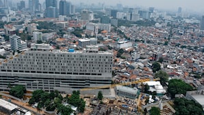 Uma extensa área urbana com uma variedade de edifícios altos e de média altura, incluindo um edifício moderno de destaque com fachada em grade.