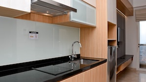 Uma cozinha moderna com bancada preta, eletrodomésticos de aço inoxidável e armários de madeira.