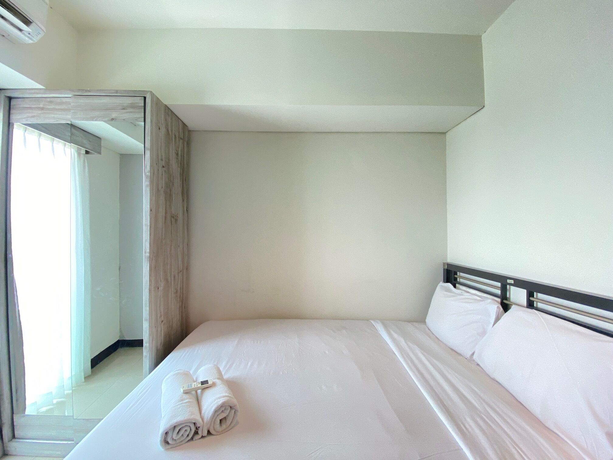 Quarto de hotel com uma cama, um guarda-roupa de madeira e vista para o exterior.