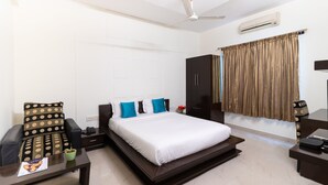 Quarto de hotel moderno com cama, sofá, escrivaninha e ventilador de teto.