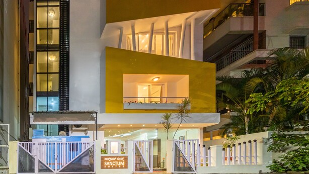 Um hotel moderno com entrada destacada, vários andares e uma varanda com plantas.