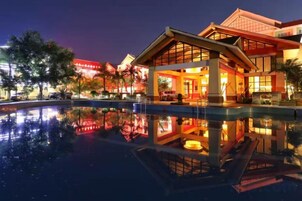 Um hotel com piscina refletindo o edifício e seus arredores.