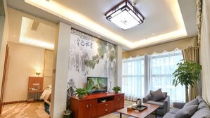 Uma sala de estar moderna com televisão de tela plana, sofá, mesa de centro e uma janela grande com cortinas.