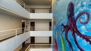 Um interior com vários níveis e design moderno, com uma escada e um mural de polvo na parede direita.