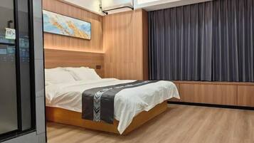 Quarto de hotel com cama, um quadro na parede, janela com cortinas e ar condicionado.