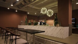Um café moderno com balcões de mármore, assentos acolchoados e plantas decorativas.