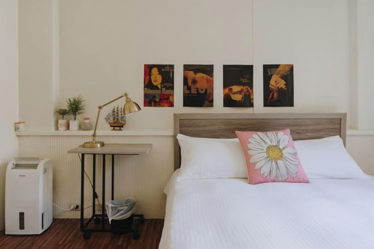 Quarto com cama, escrivaninha, luminária e obras de arte na parede.
