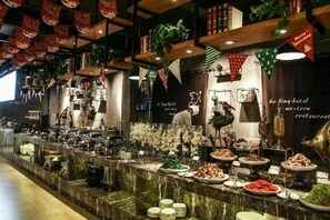 Disposição de buffet com diversos alimentos e um bartender preparando bebidas.
