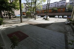 Uma área de estacionamento com vários carros, árvores e um edifício ao fundo.