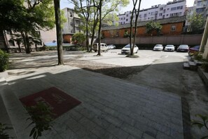 Uma área de estacionamento com vários carros, árvores e um edifício ao fundo.
