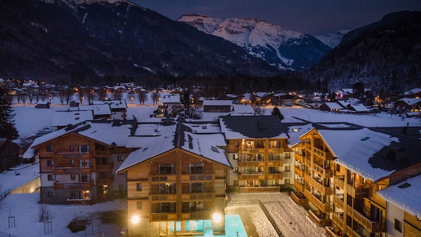 Estância coberta de neve com área de piscina, rodeada por montanhas.