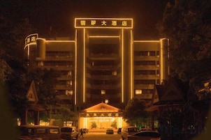 Um hotel de vários andares com entrada imponente e sinalização iluminada.