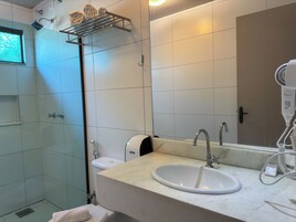 Casa de banho com lavatório, espelho, porta-toalhas e chuveiro.