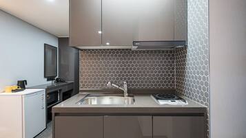 Uma cozinha moderna com micro-ondas embutido, pia de aço inoxidável e fogão a gás.