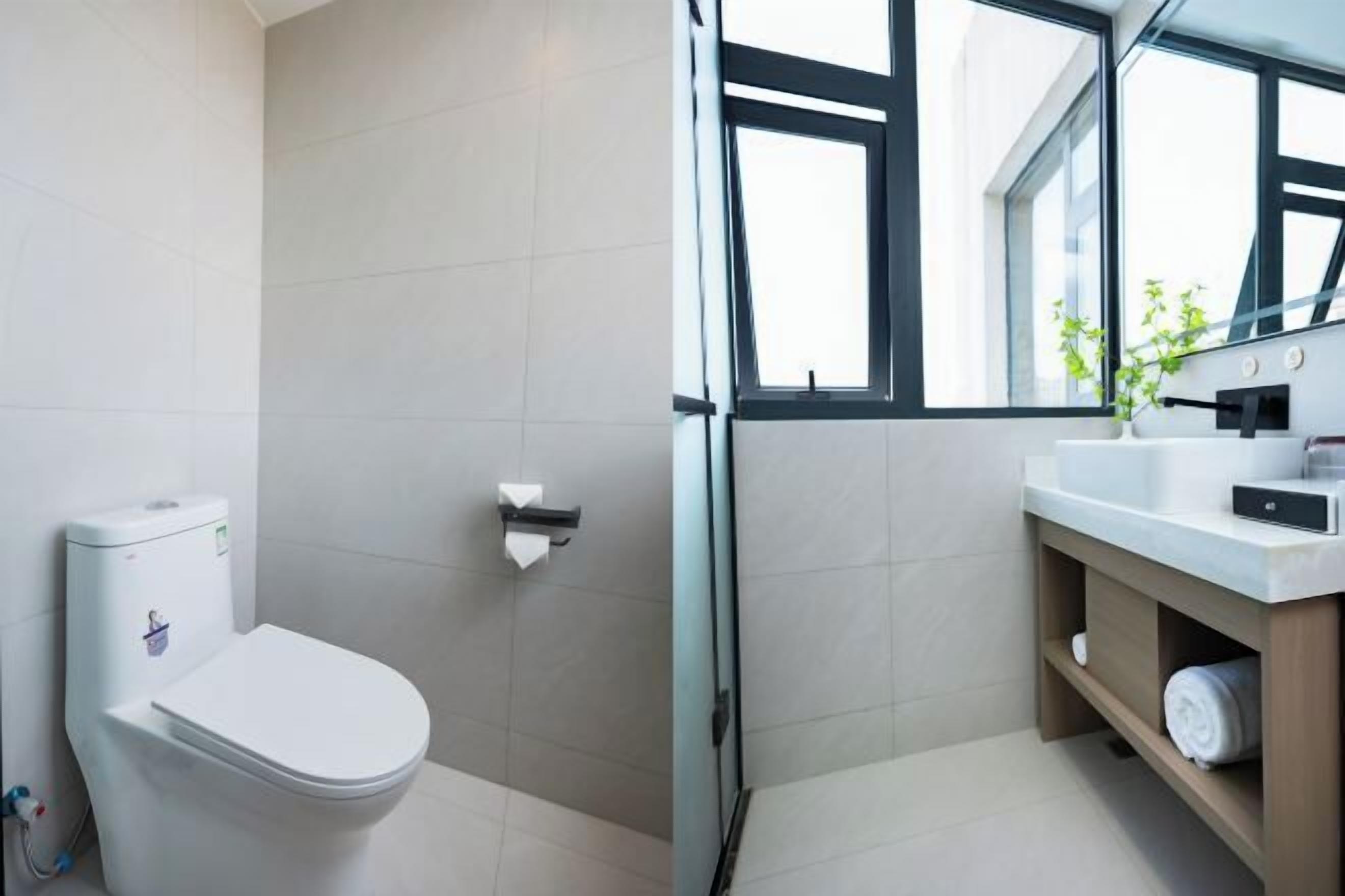 Uma casa de banho moderna com sanita, cabine de duche em vidro e lavatório com espelho em cima.
