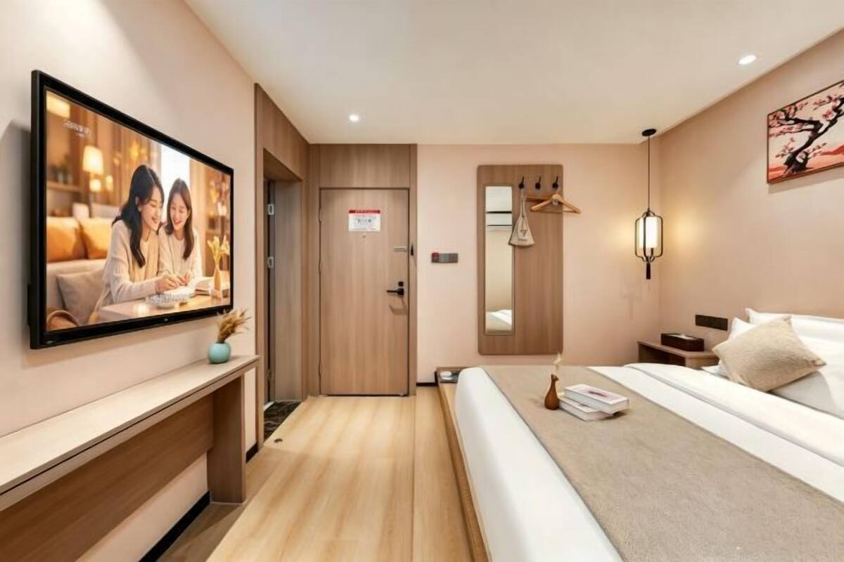 Quarto de hotel moderno com cama, televisão, escrivaninha e guarda-roupa.