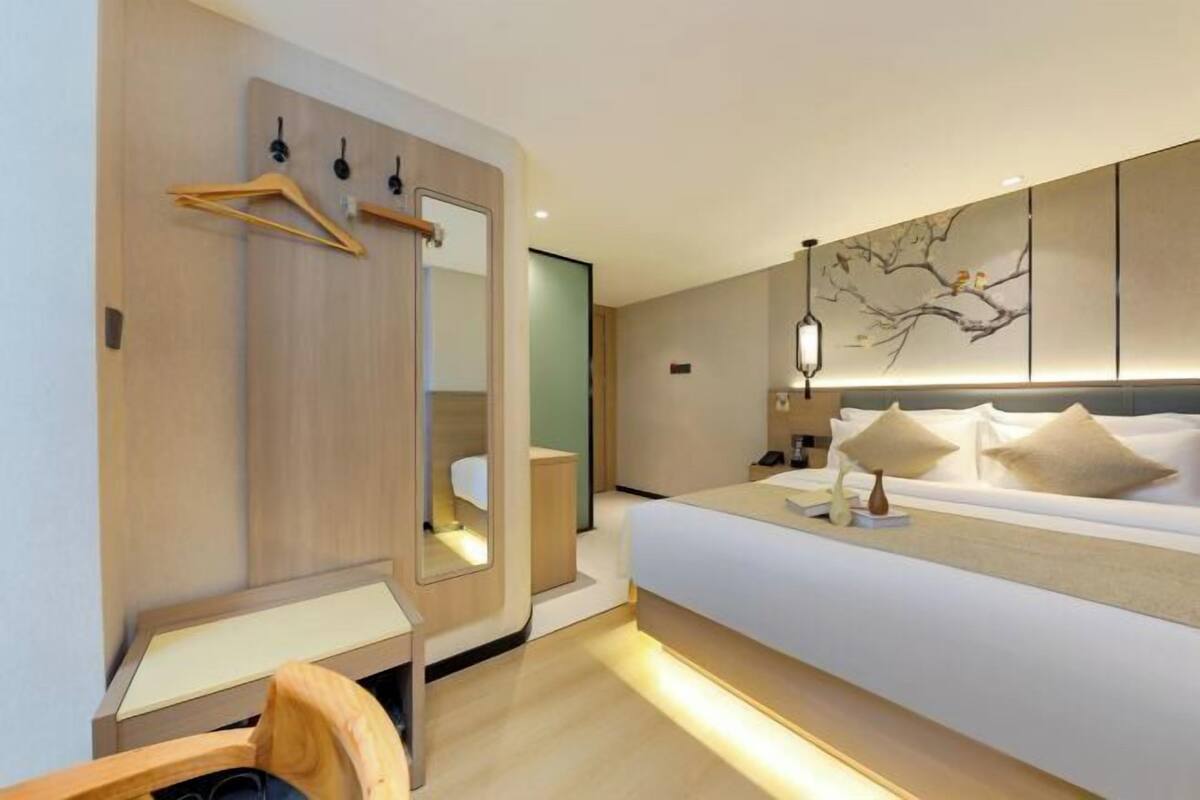 Quarto moderno com uma cama grande, guarda-roupa de madeira, um espelho e uma obra de arte pendurada na parede.