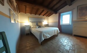 Um quarto com cama, mesas de cabeceira, penteadeira e janela.