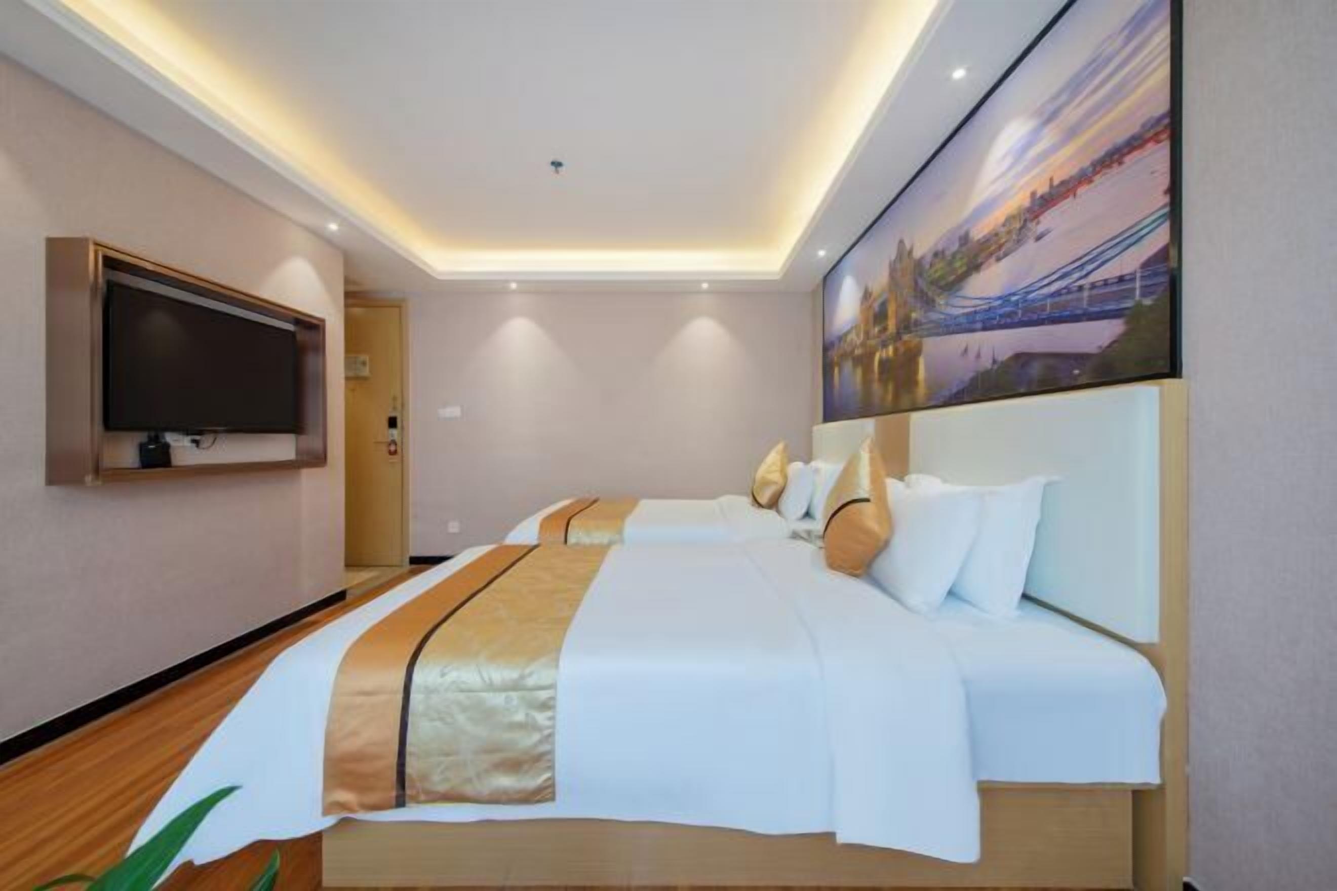 Quarto de hotel com uma cama grande, televisão de tela plana na parede e um quadro de uma ponte.