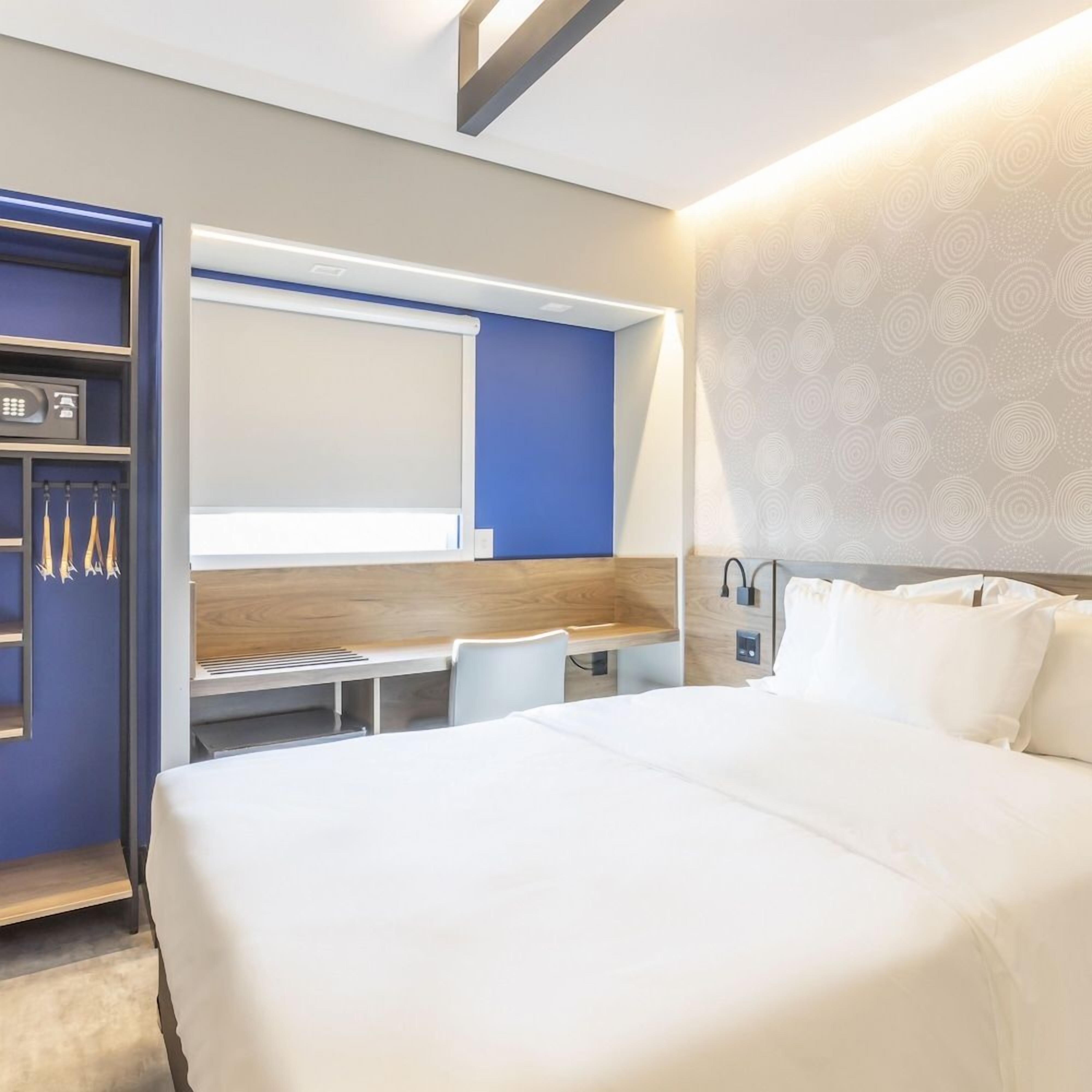 Quarto de hotel com uma cama grande, uma escrivaninha e um guarda-roupa.