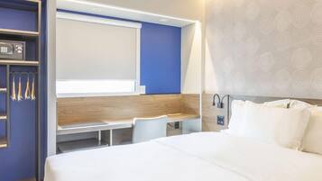 Quarto de hotel com uma cama grande, uma escrivaninha e um guarda-roupa.