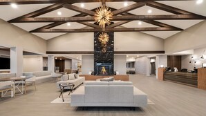 Uma sala de estar ampla com lareira, móveis modernos e vigas de madeira aparente.