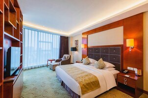 Quarto de hotel com uma cama grande, mesas de cabeceira, uma escrivaninha e uma cadeira.