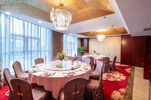 Uma sala de conferências com mesas redondas, cadeiras e lustres.