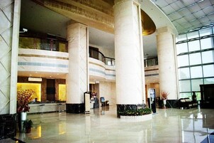 Um hall amplo com pé direito alto, grandes colunas e uma área de recepção central.