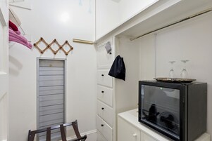Quarto compacto com cozinha compacta, uma pequena televisão e janela com persianas.