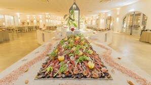 Uma ampla sala de banquetes com um display central de frutos do mar, várias mesas de jantar e um design arquitetônico moderno.
