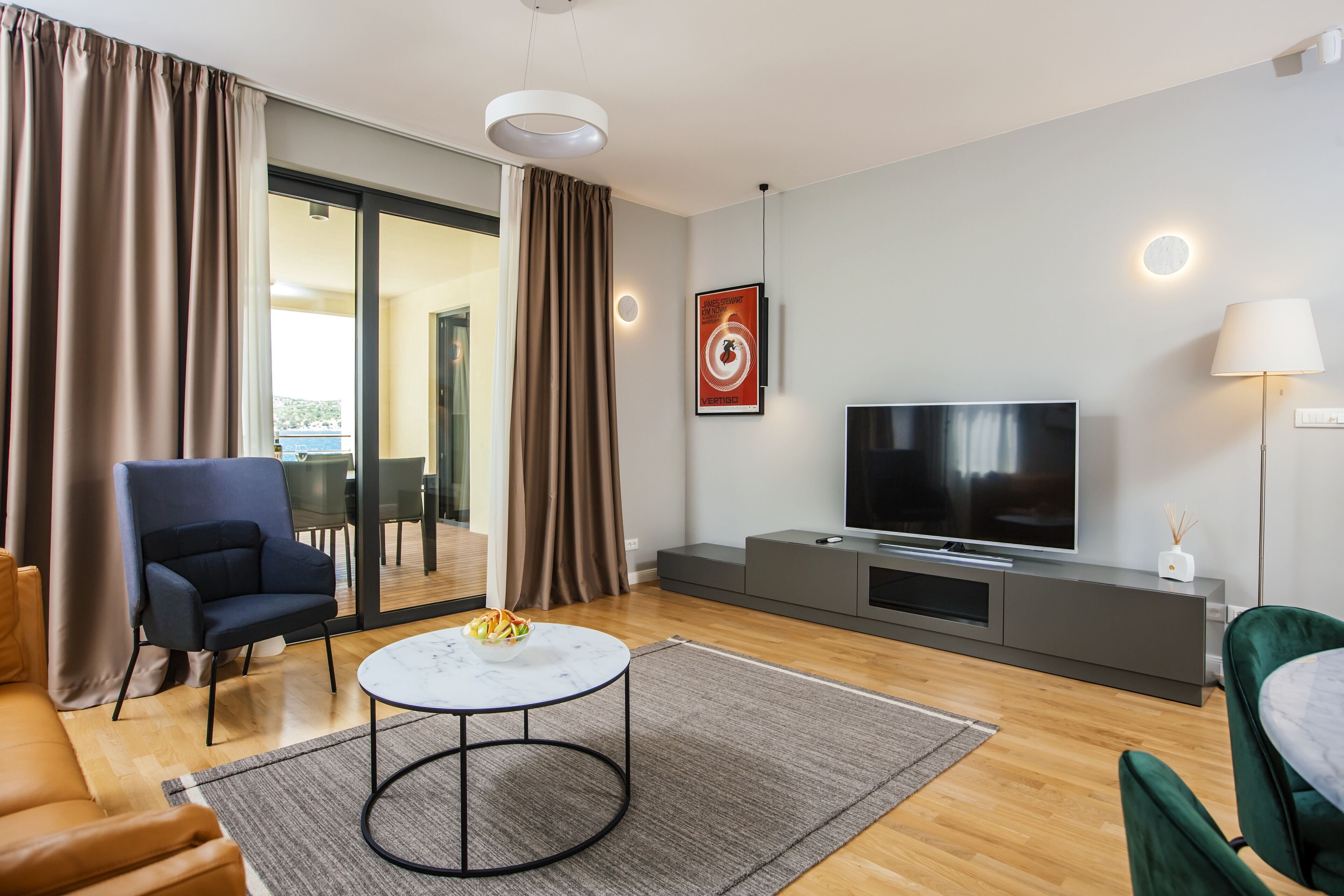Uma sala de estar moderna com uma TV de tela plana, uma mesa de centro redonda e um sofá.