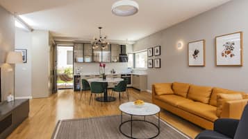 Uma sala de estar moderna com sofá, mesa de centro e área de jantar com cadeiras.