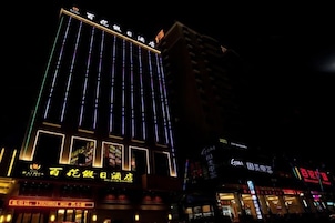 Edifício de vários andares com linhas verticais iluminadas e sinalização.
