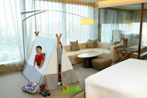 Quarto de hotel com sofá, mesa redonda pequena, área de recreação tipo tenda e uma cama.