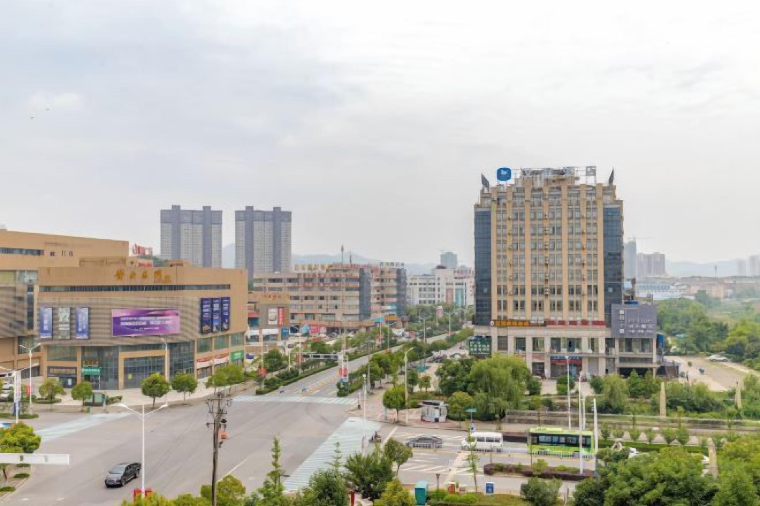 Paisagem urbana com edifícios modernos, uma avenida larga e áreas verdes.