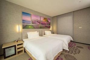 Quarto de hotel com duas camas, uma grande obra de arte na parede, televisão de tela plana e um tapete estampado.