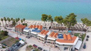 Um hotel à beira-mar com vários edifícios, uma praia com guarda-sóis e espreguiçadeiras, e vista para o mar.
