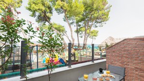 Uma varanda com mesa posta para o café da manhã, com vista para um parquinho com escorregadores e piscina.