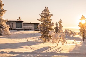 Paisagem coberta de neve com um edifício de janelas amplas e telhado plano.